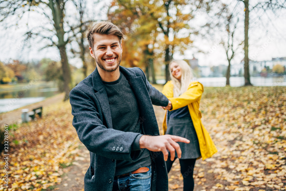 young couple having fun outdoors in autumn park, fall. Loughing and ...
