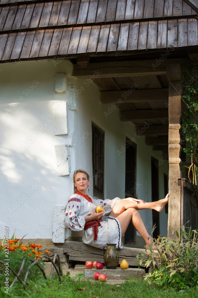 Ukrainian girl sits near the village house in embroidered dress in the ...