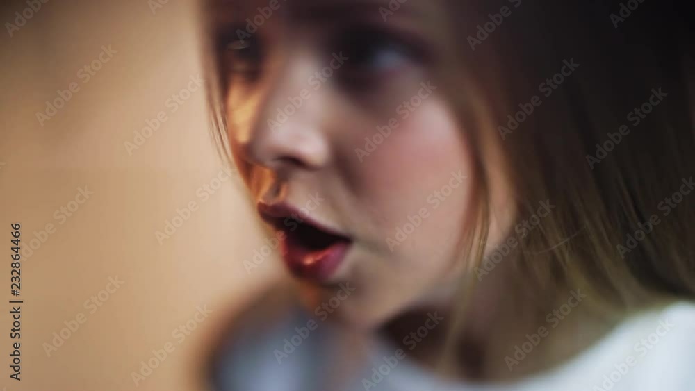 Close up face young blonde girl makes an angry face talk speak white ...