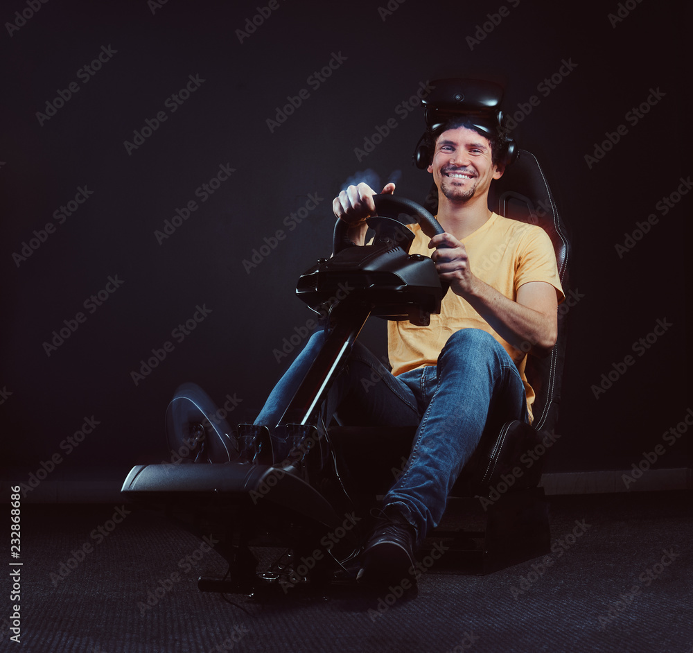Joyful man dressed in yellow shirt and jeans in VR headset sitting on a ...