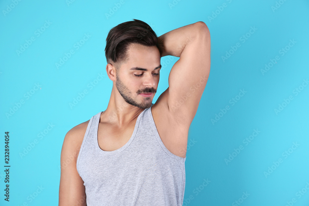 Handsome young man showing armpit on color background. Using deodorant ...