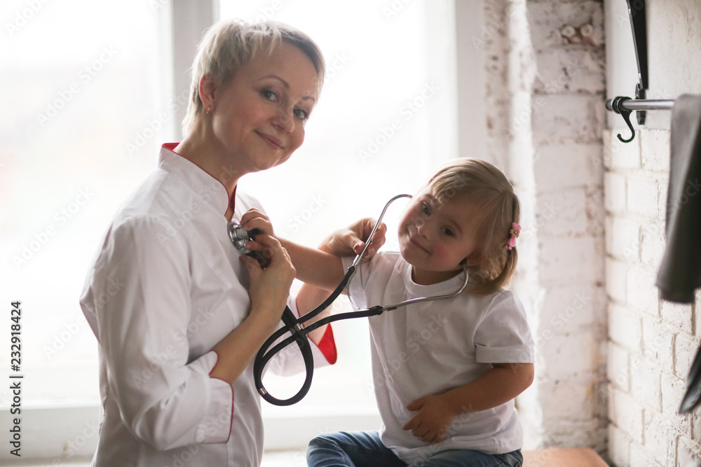 doctor listens heart of child with Down syndrome Stock Photo | Adobe Stock