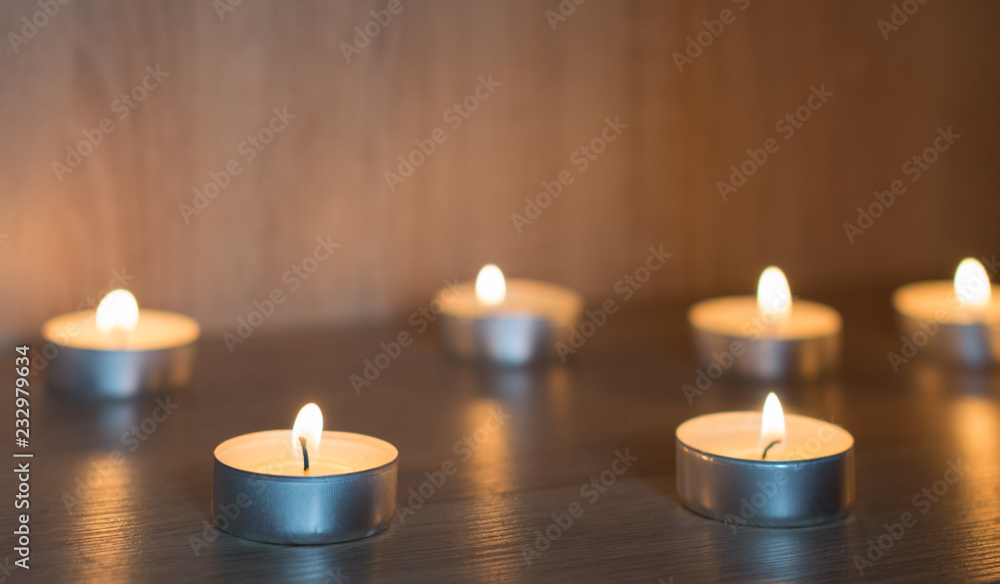 Burning candles. Small round tea light candles on wooden table front ...