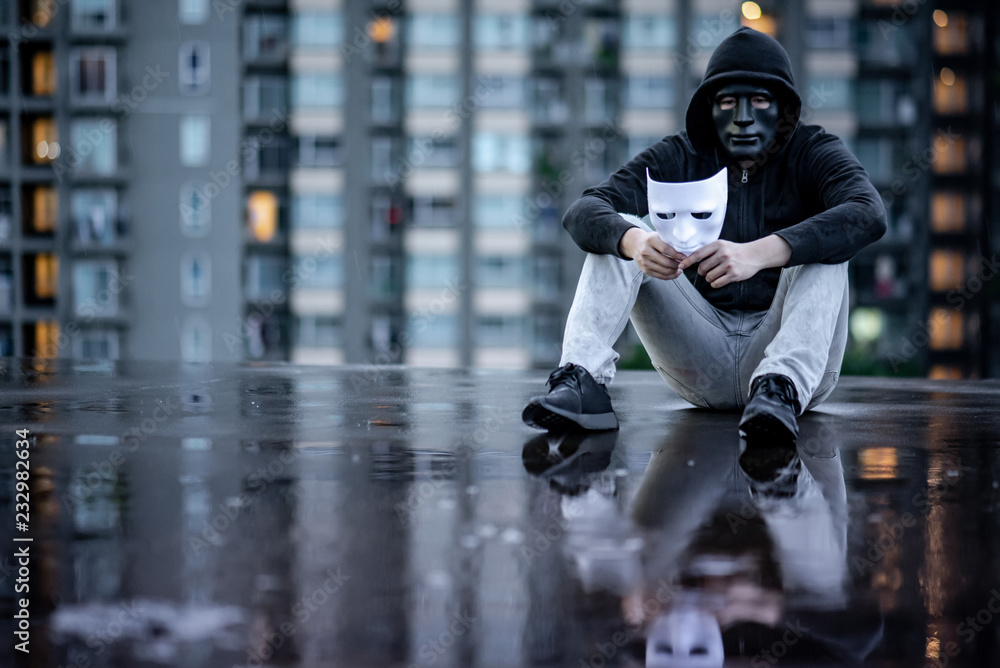 Reflection of mystery hoodie man with black mask holding white mask ...