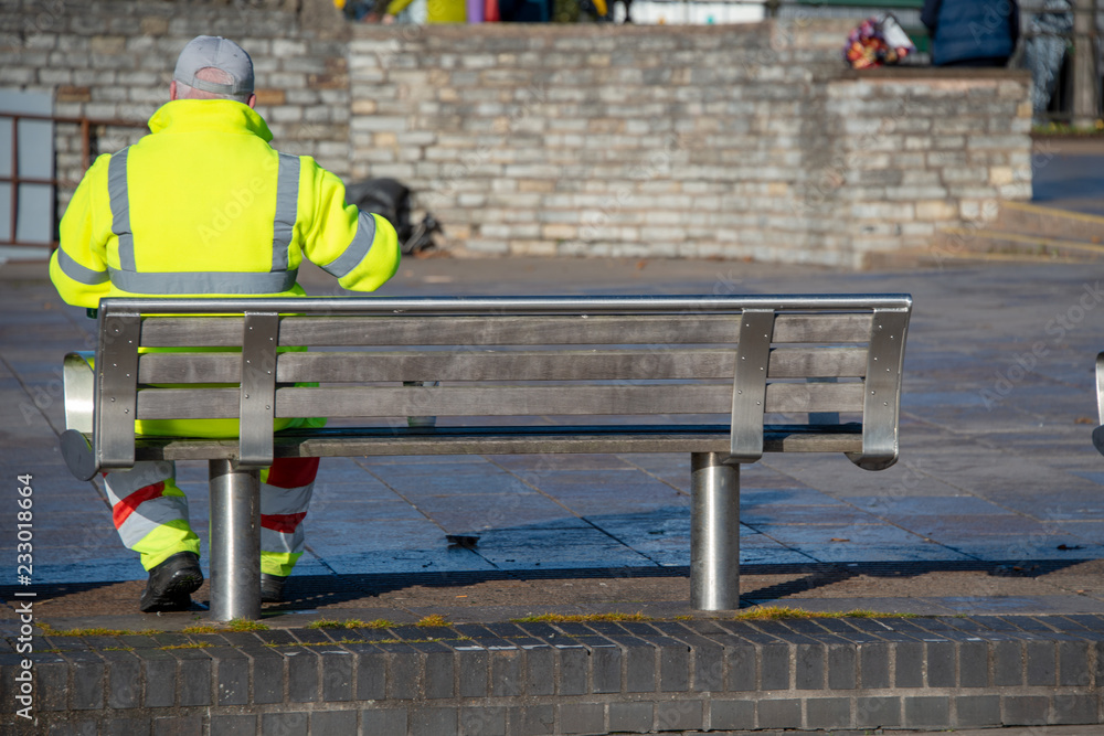 street cleaner wearing hi vis jacket and trousers has a quick coffee or ...