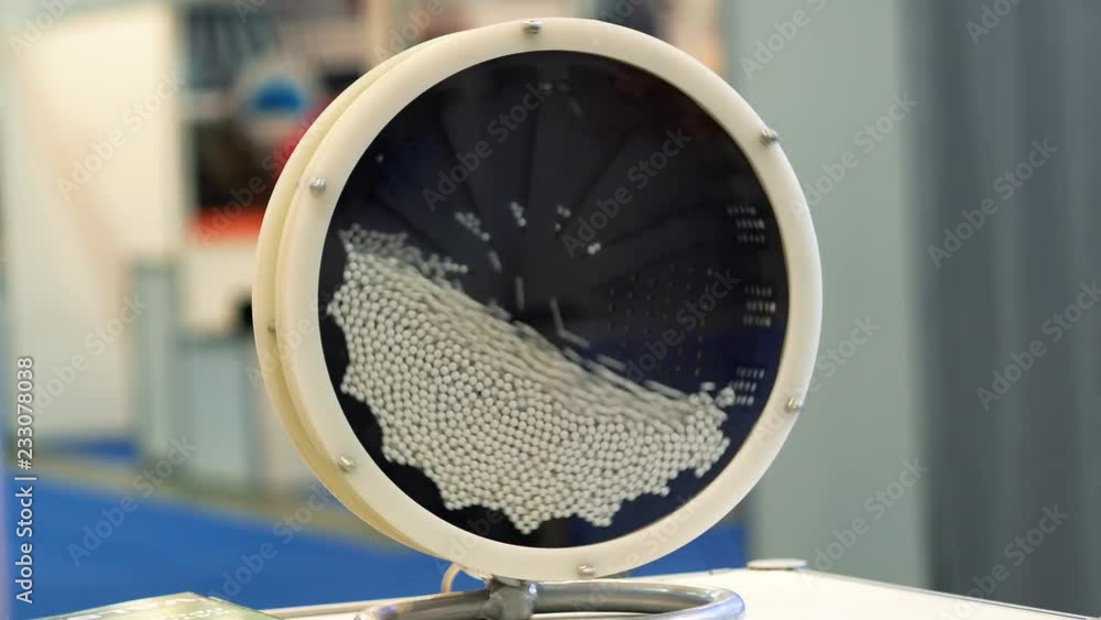 Small white balls inside a round container. Perpetual motion machine ...