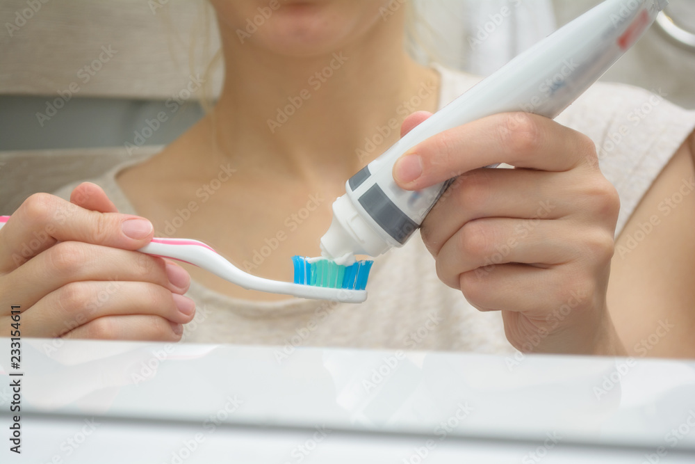Woman hand holding a toothbrush with a toothpaste applied on it in the ...