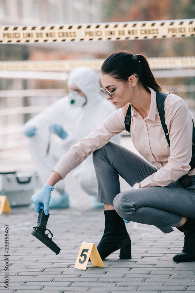 female detective taking gun as a clue with criminologist behind her at ...
