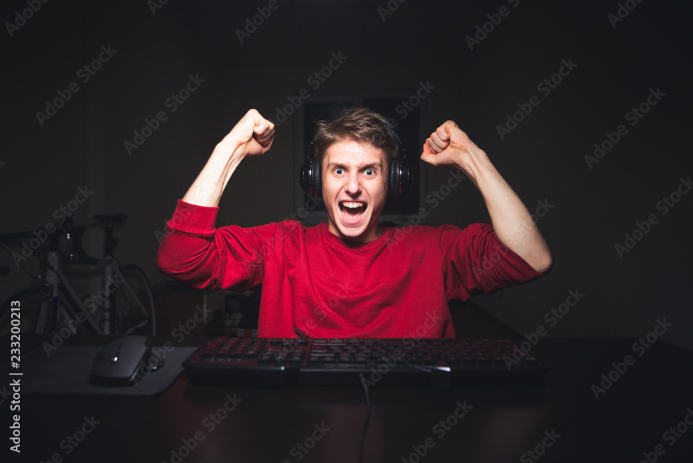 Portrait of an emotional gamer rejoicing with his hands up. Young man ...