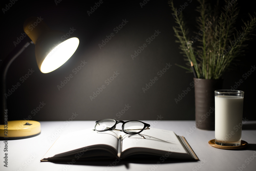 Glasses placed on the book, Open book, Glass of milk and flower vases ...
