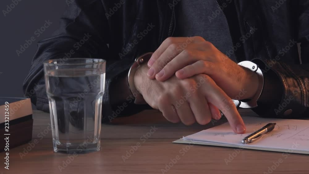 Vidéo Stock Handcuffed male criminal in black leather jacket is giving ...