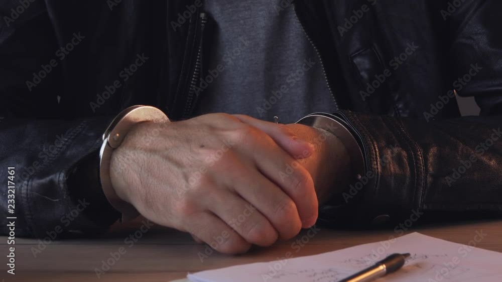 Handcuffed criminal in black leather jacket is giving statement during ...