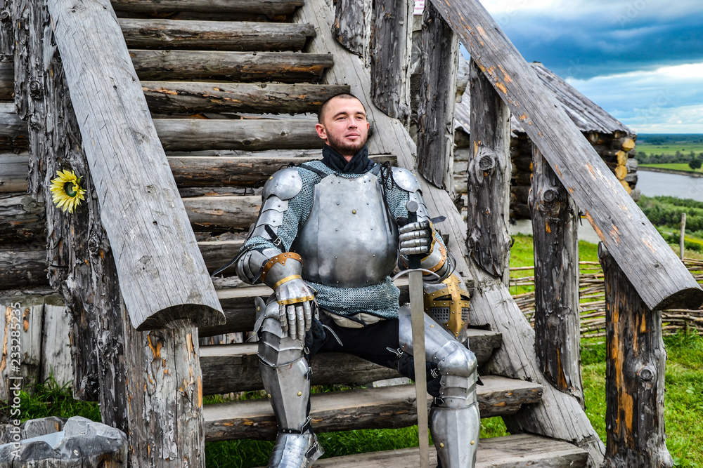 Knight in the armor on the wooden steps. Knightly armor and weapon ...
