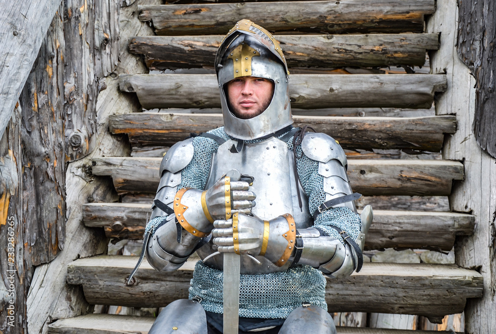 Knight in the armor on the wooden steps. Knightly armor and weapon ...