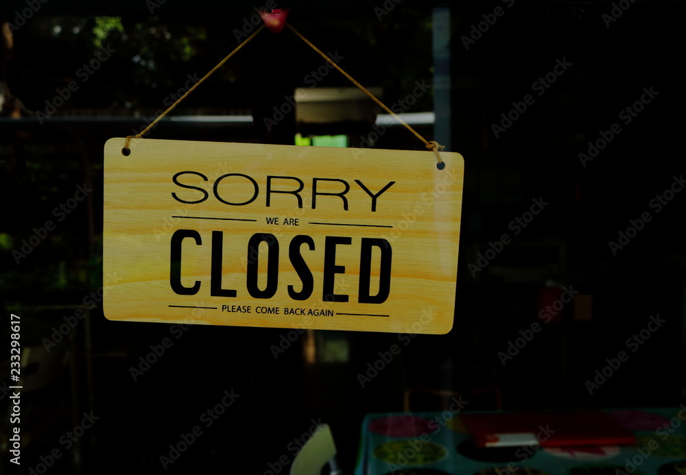a wooden closed sign hanging on window of a shop with words read sorry ...