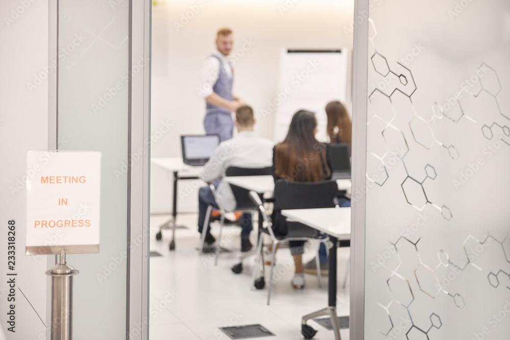 sign "Meeting in progress", standing in front of office, while ...
