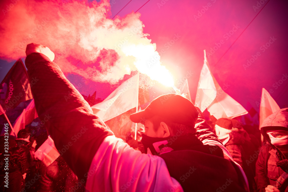 Foto de People carry Polish flags and burn flares as they walk across ...