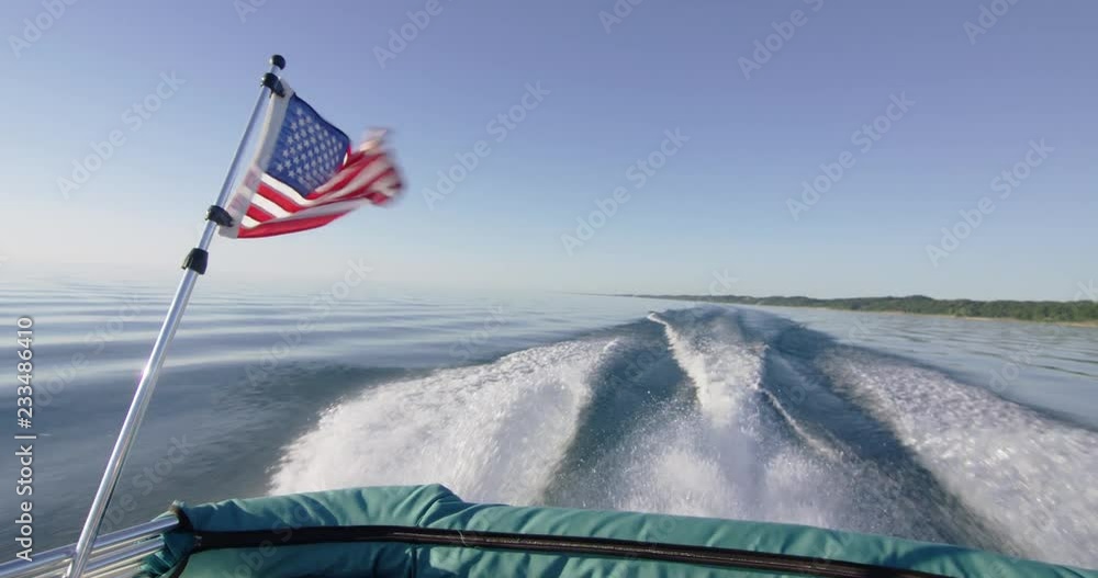 Vidéo Stock American sail flag waves in the back of a boat as water ...
