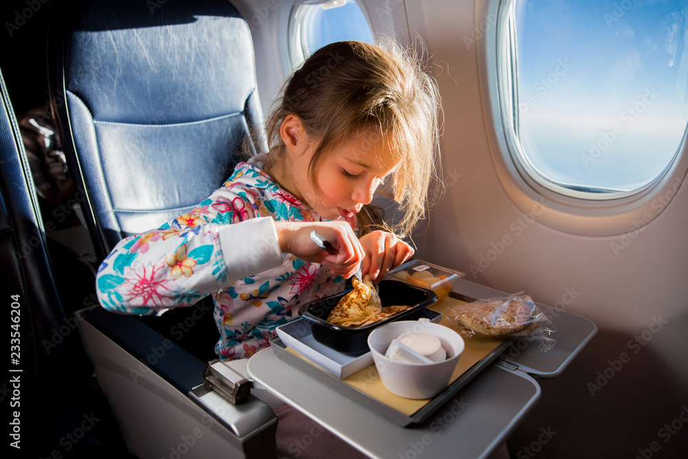 Child eating pancakes in airplane. Little girl having breakfast while ...