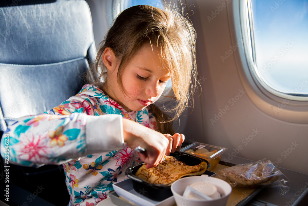 Child eating pancakes in airplane. Little girl having breakfast while ...