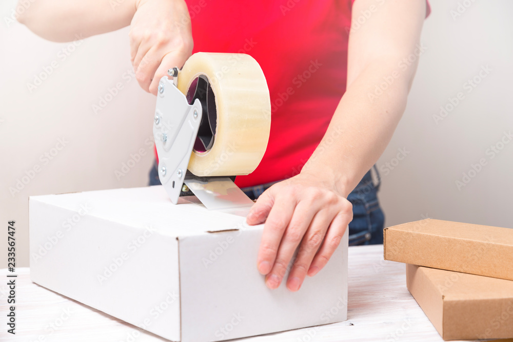 Woman packing cardboard boxes using tape dispenser Stock Photo | Adobe ...