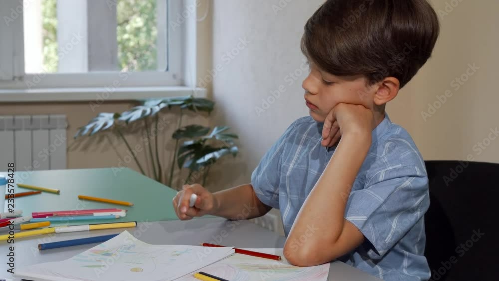 Young schoolboy looking bored while coloring his sketchbook. Cute ...