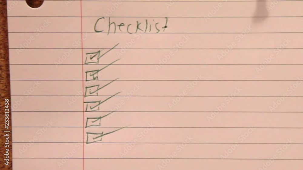 A hand holds a green pen and ticks off boxes on a piece of paper ...