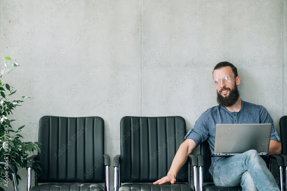 smiling man touching empty chair beside him. invitation and job ...