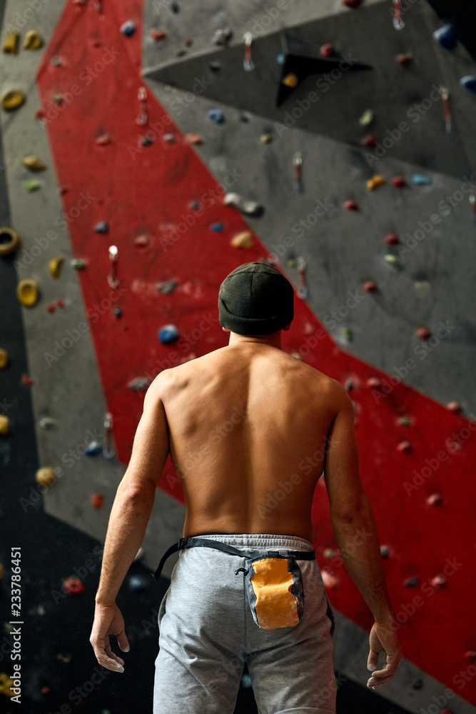 Caucasian rock climber with naked muscular torso, equipped with safety ...