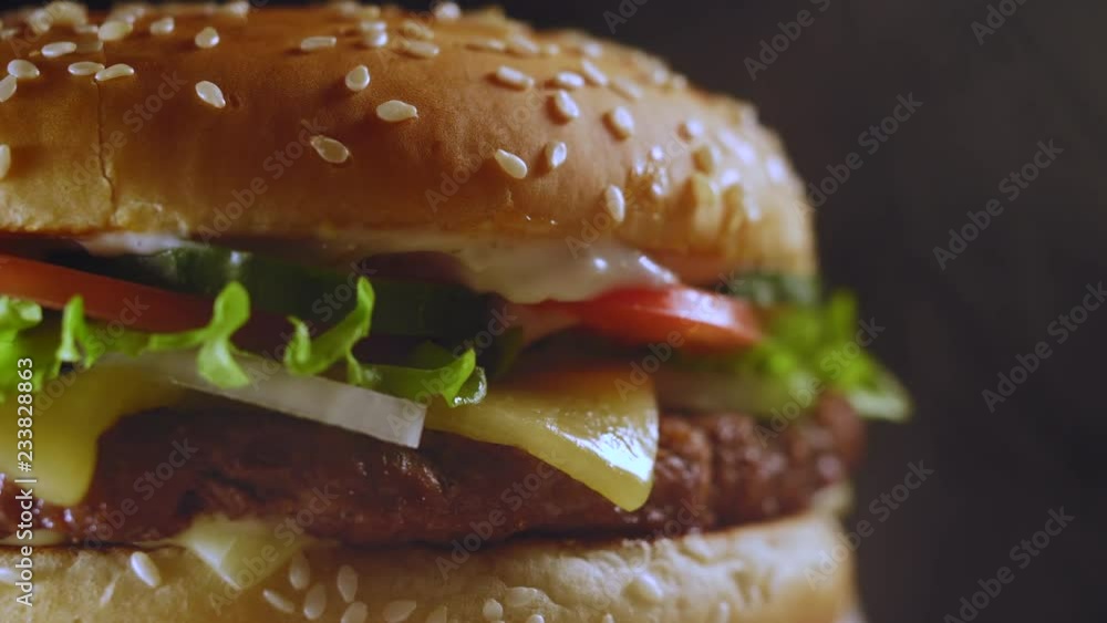 Giant delicious fresh burger rotating on dark smoke background ...