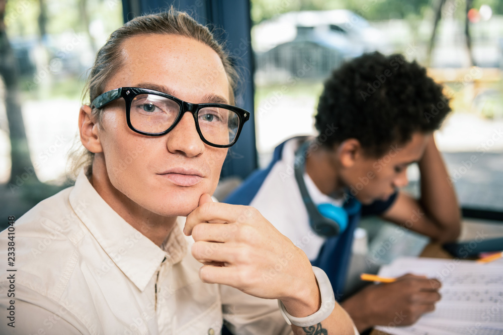 Very smart. Portrait of a serious young man looking at you while having ...