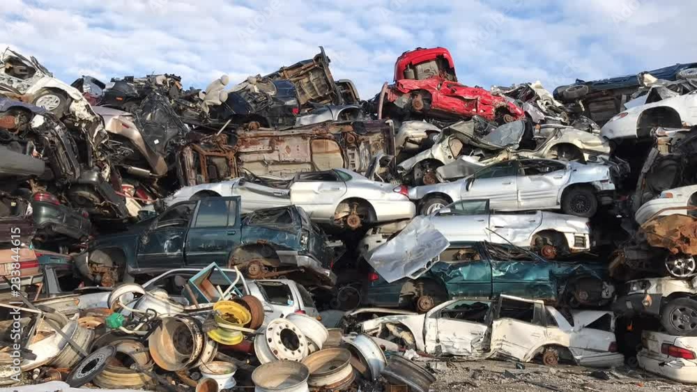 Cars stacked up in junk yard time lapse with clouds moving in ...