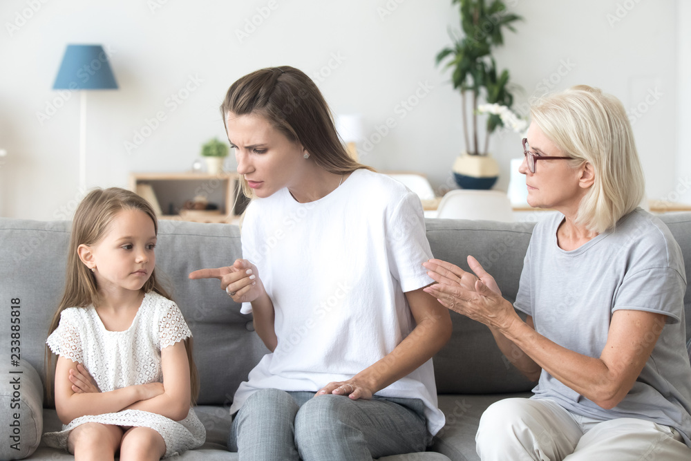 Angry young mother scolding child daughter while old grandmother ...
