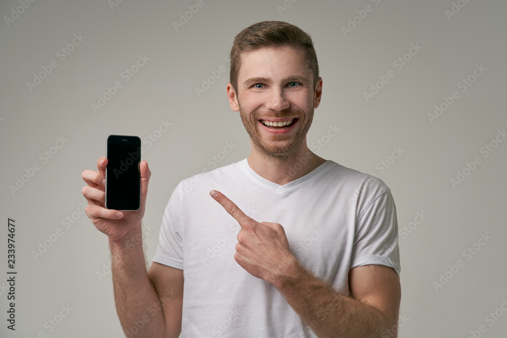Handsome guy with index finger shows blank phone screen where you can ...