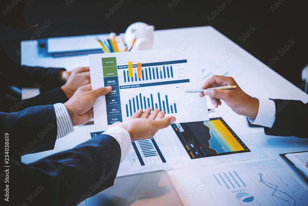 Business people discussing and pointing charts ,graphs results report ...