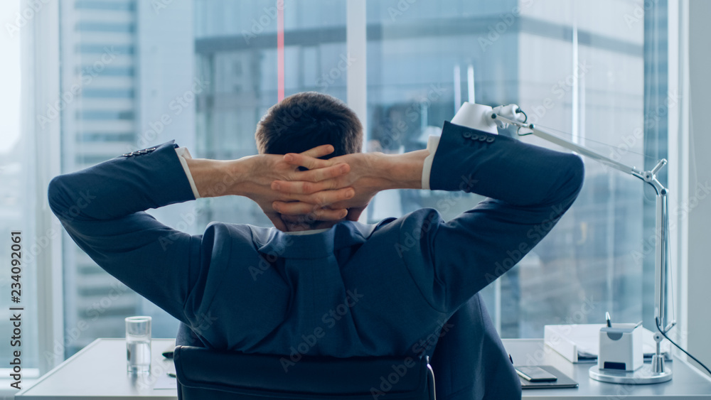 Back View of Confident Businessman Sitting at His Desk and Stretches ...