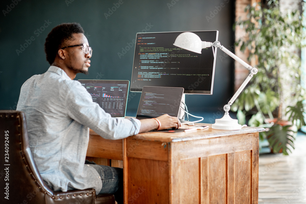 Young african male programmer writing program code sitting at the ...