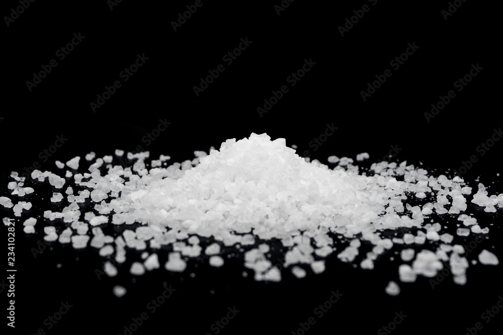 Spilled white sea salt on a black background. Transparent pebbles on a ...