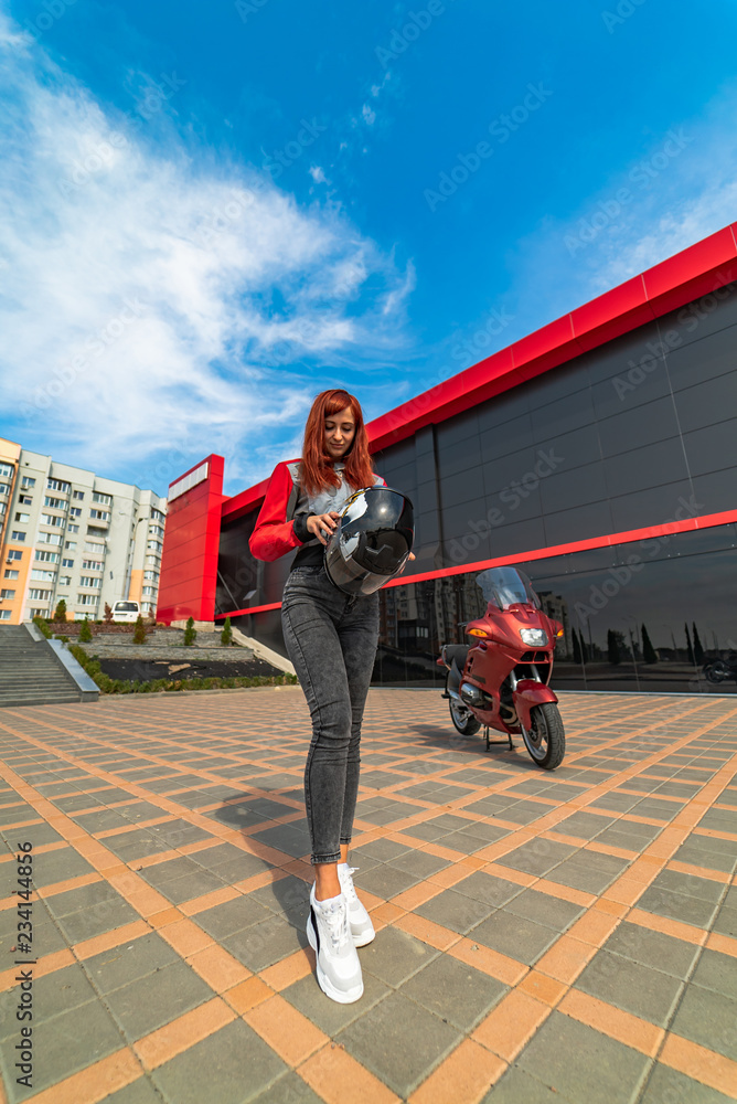 Young attractive woman with red hair in grey jeans putting on her ...