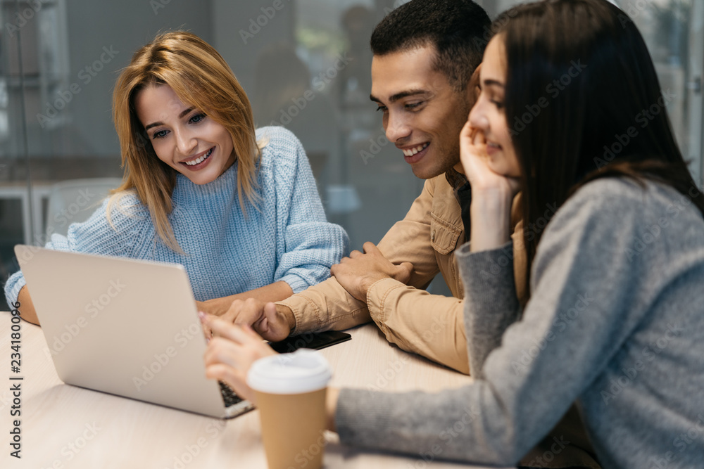 Happy multiethnic university students using laptop computer and ...