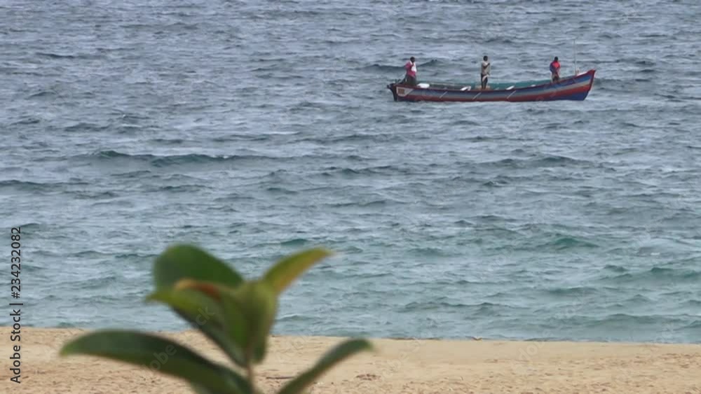 A steady, long shot with three fishermen at work, on a wooden boat ...