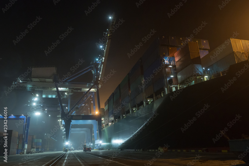 Foto de Container ship in port at container terminal in fog weather ...