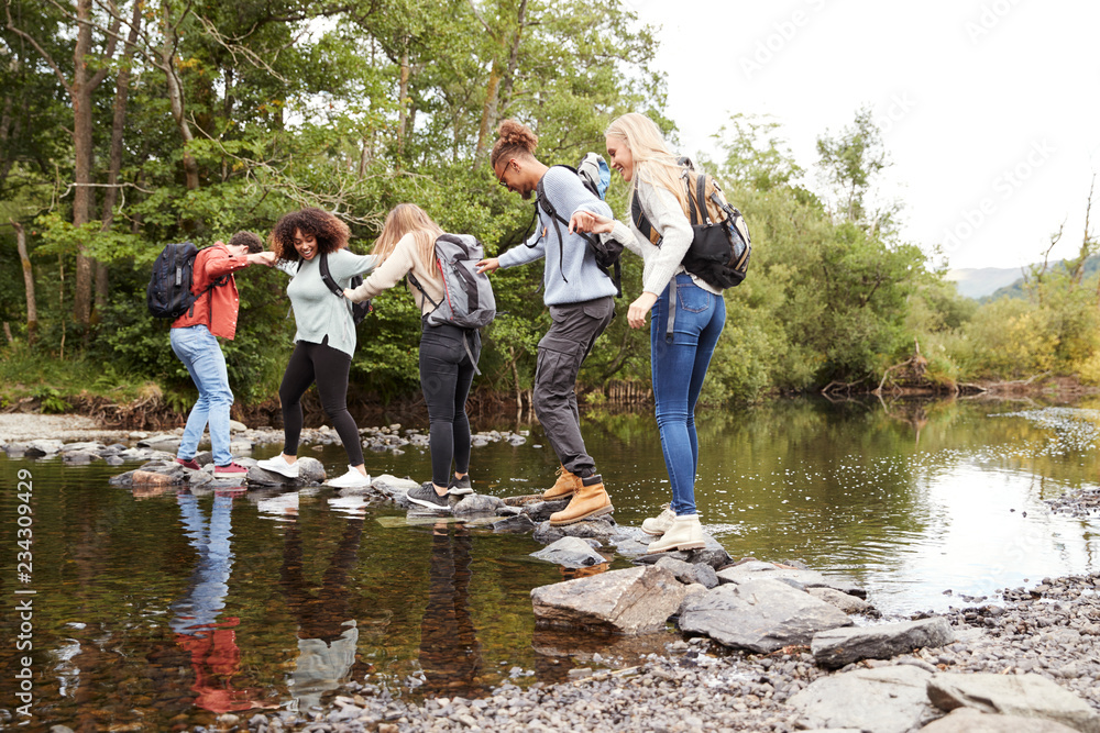 Multi ethnic group of five young adult friends hold hands balancing on ...