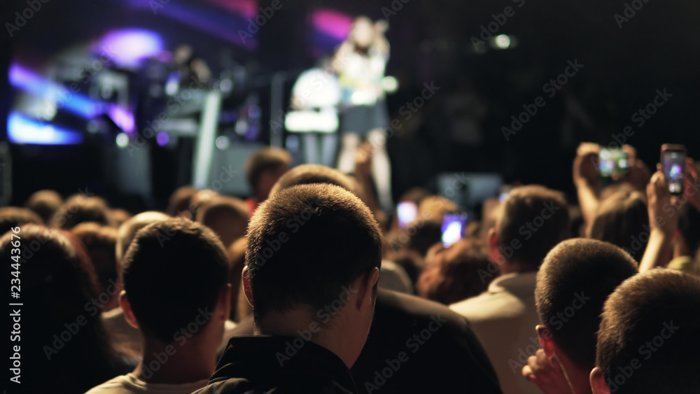 Silhouettes of concert crowd in front of bright stage lights. Public ...
