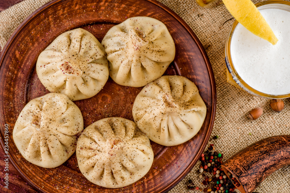 national Georgian dish. khinkali on a brown clay plate and beer with ...