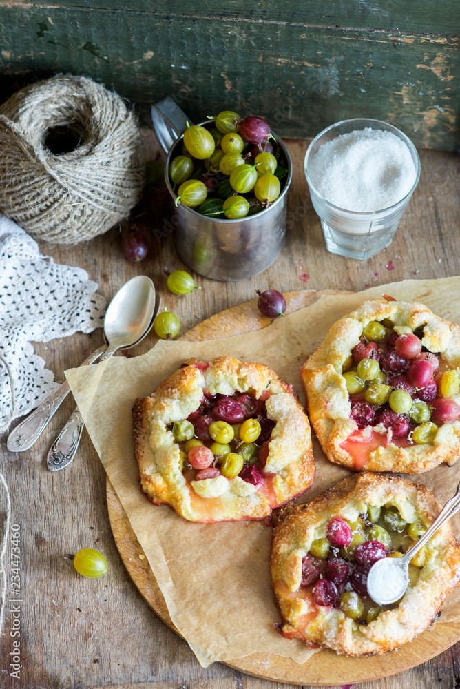 Overhead view of shortcrust pastry gooseberry pies on parchment paper ...