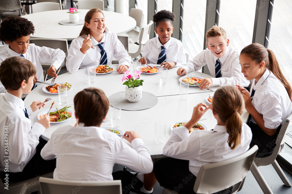 Group Of High School Students Wearing Uniform Sitting Around Table And ...