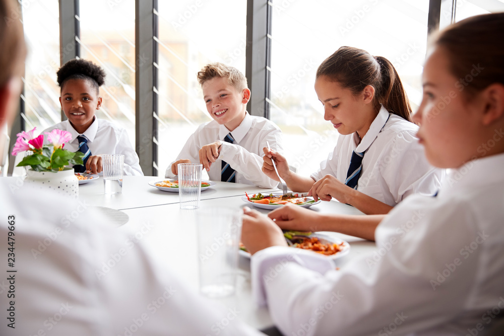 Group Of High School Students Wearing Uniform Sitting Around Table And ...
