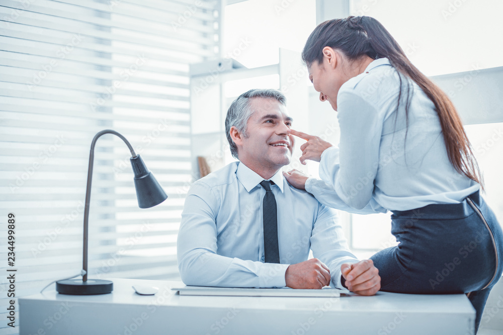 Smiling boss. Long-haired beautiful female sitting on the table and ...