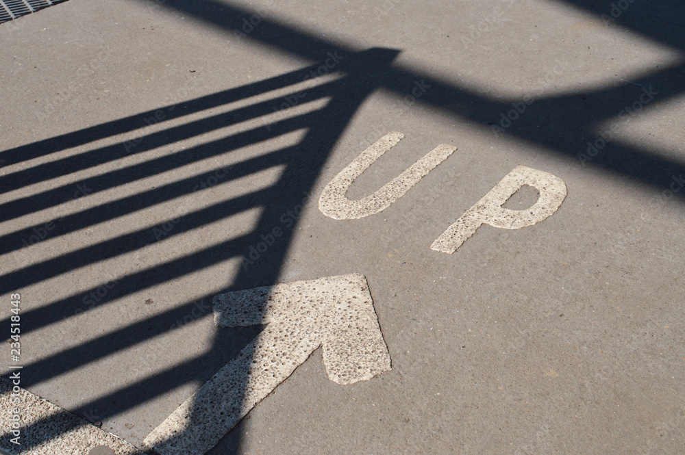 sign of an arrow with the words UP meaning go upstairs with the shadow ...